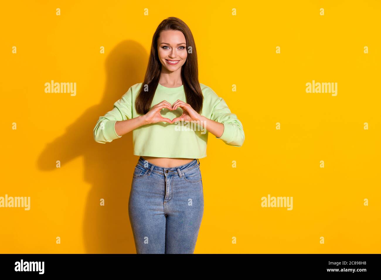 Photo of attractive pretty lady good mood hold arms making heart figure ...