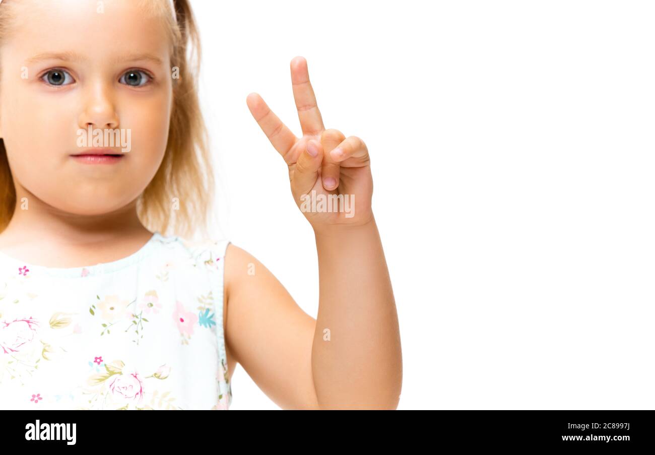 Peace symbol. Little girl gesturing isolated on white studio background ...