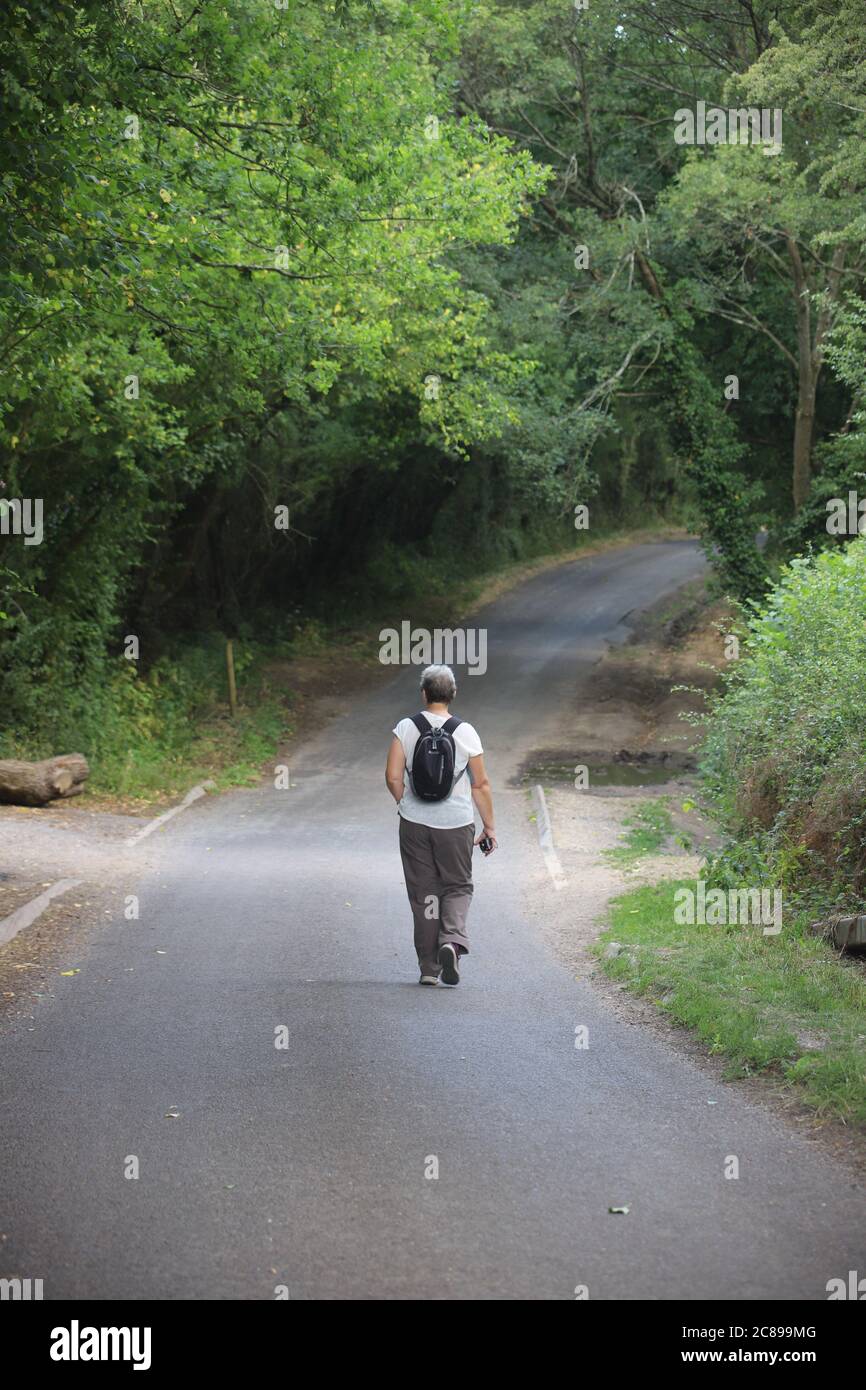 rear view of lone female walker on a country road Stock Photo - Alamy
