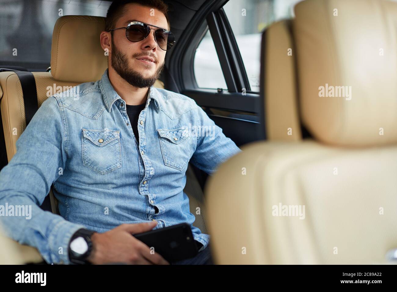 pleasant cool guy having a rest on the back seat of the Mercedes ...