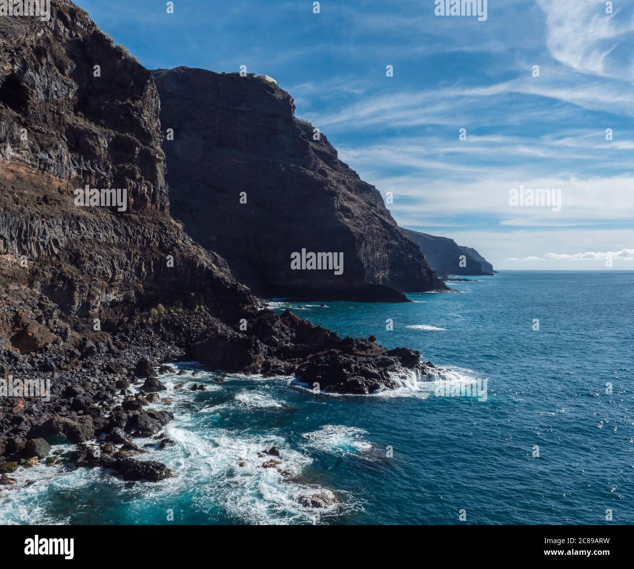High steep Volcanic rock cliffs of black lava on the rocky shore with ...