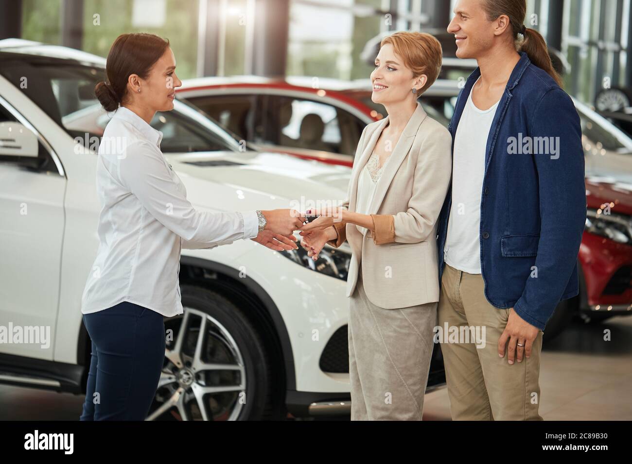 New car owners. Happy young blonde couple dressed in formal wear ...