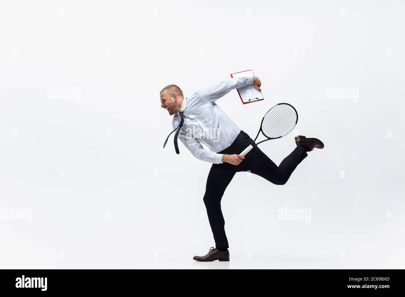 Time for movement. Man in office clothes plays tennis isolated on white ...