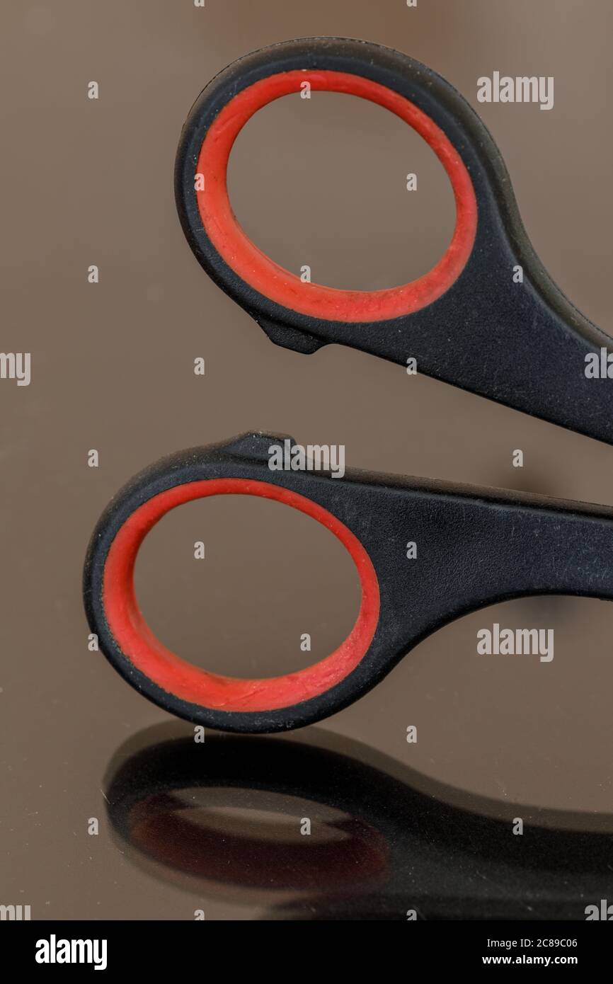 Macro shot of the scissors coloured handles which are reflected in the ...