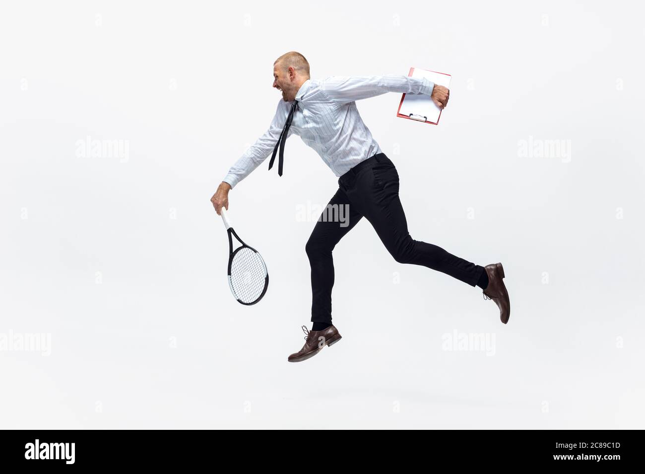 Time for movement. Man in office clothes plays tennis isolated on white ...