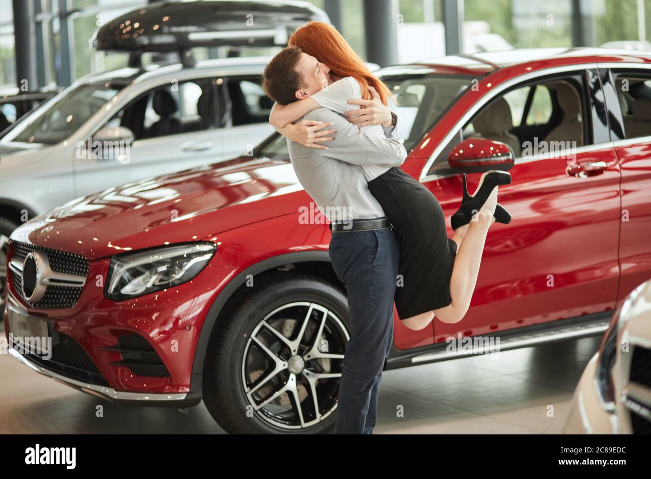 Happy young lovely couple hugging while buying first new family car ...