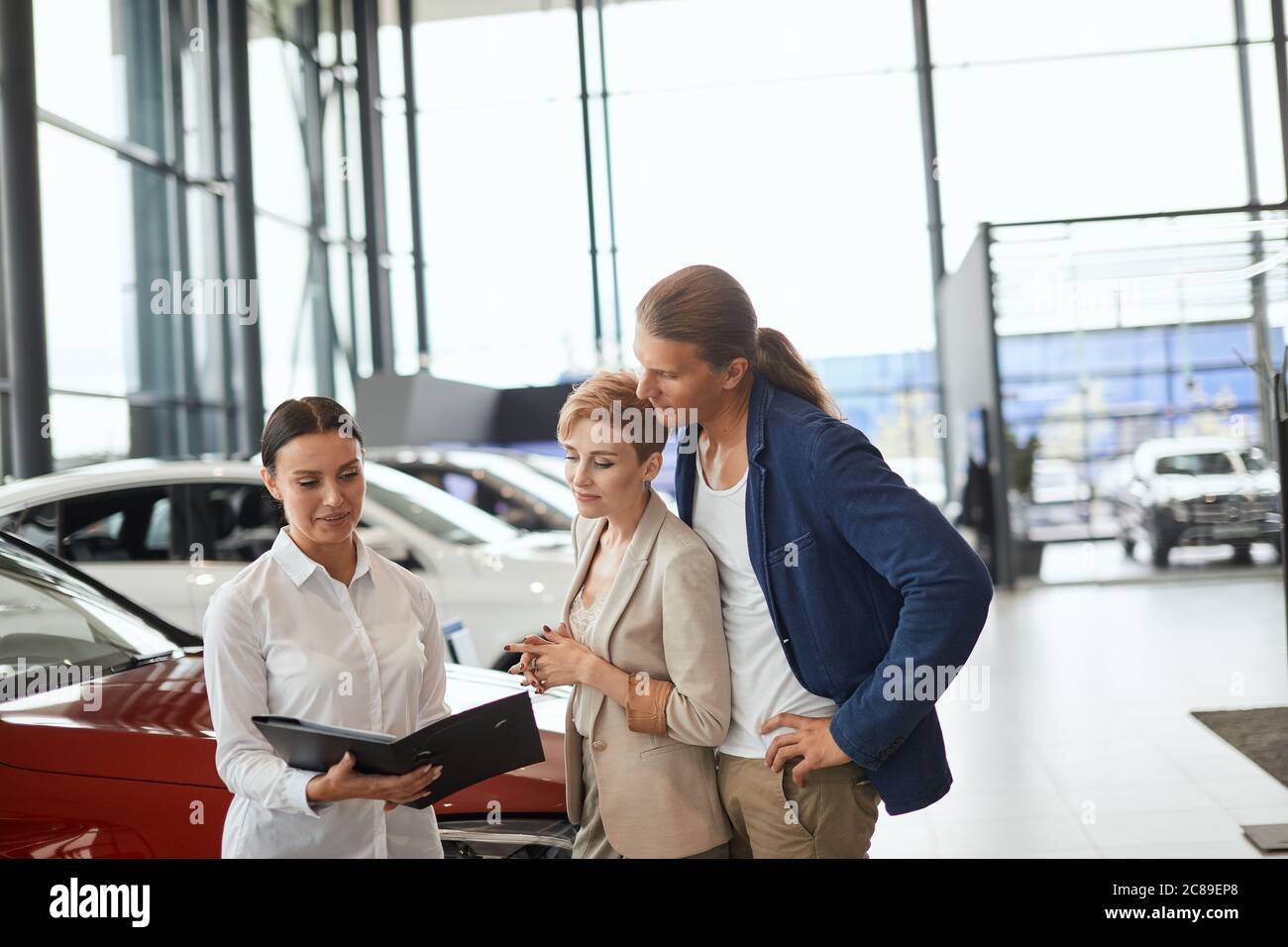 Female sales manager standing at the dealership telling about the ...