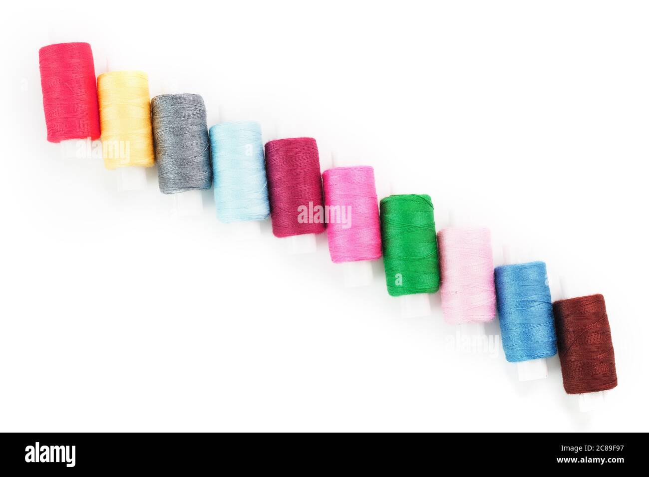 Sewing threads of different colors on reels on a white background. Free ...