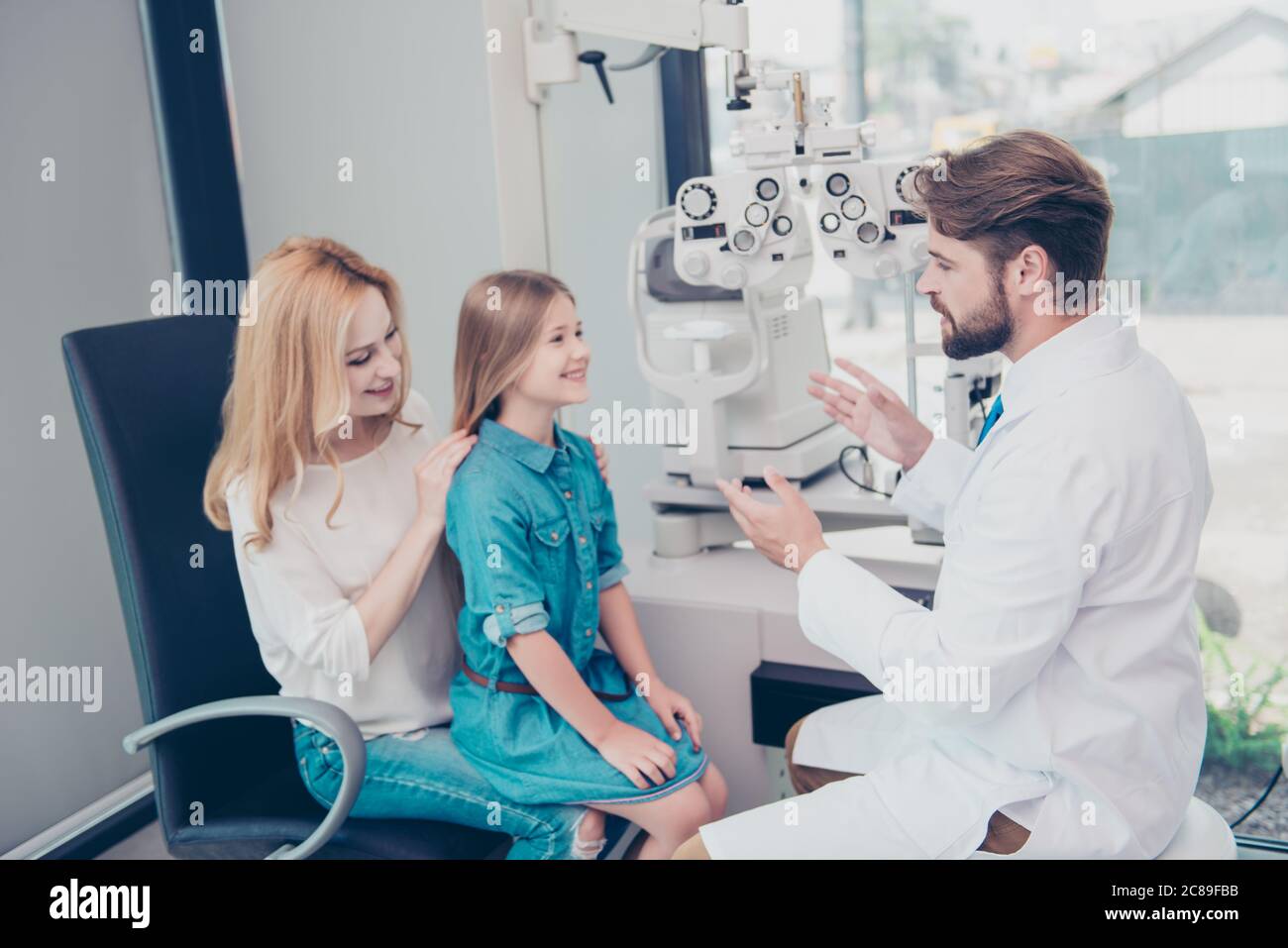 Optometrist consultation. Blond mom with smiling joyful girl are ...