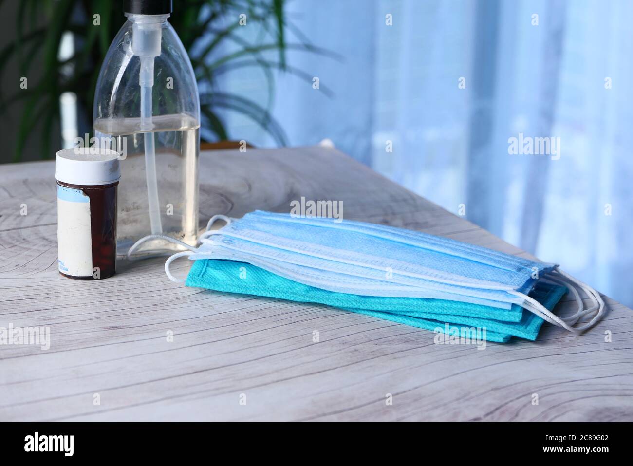 Surgical masks, pill container and hand sanitizer on wooden table Stock ...
