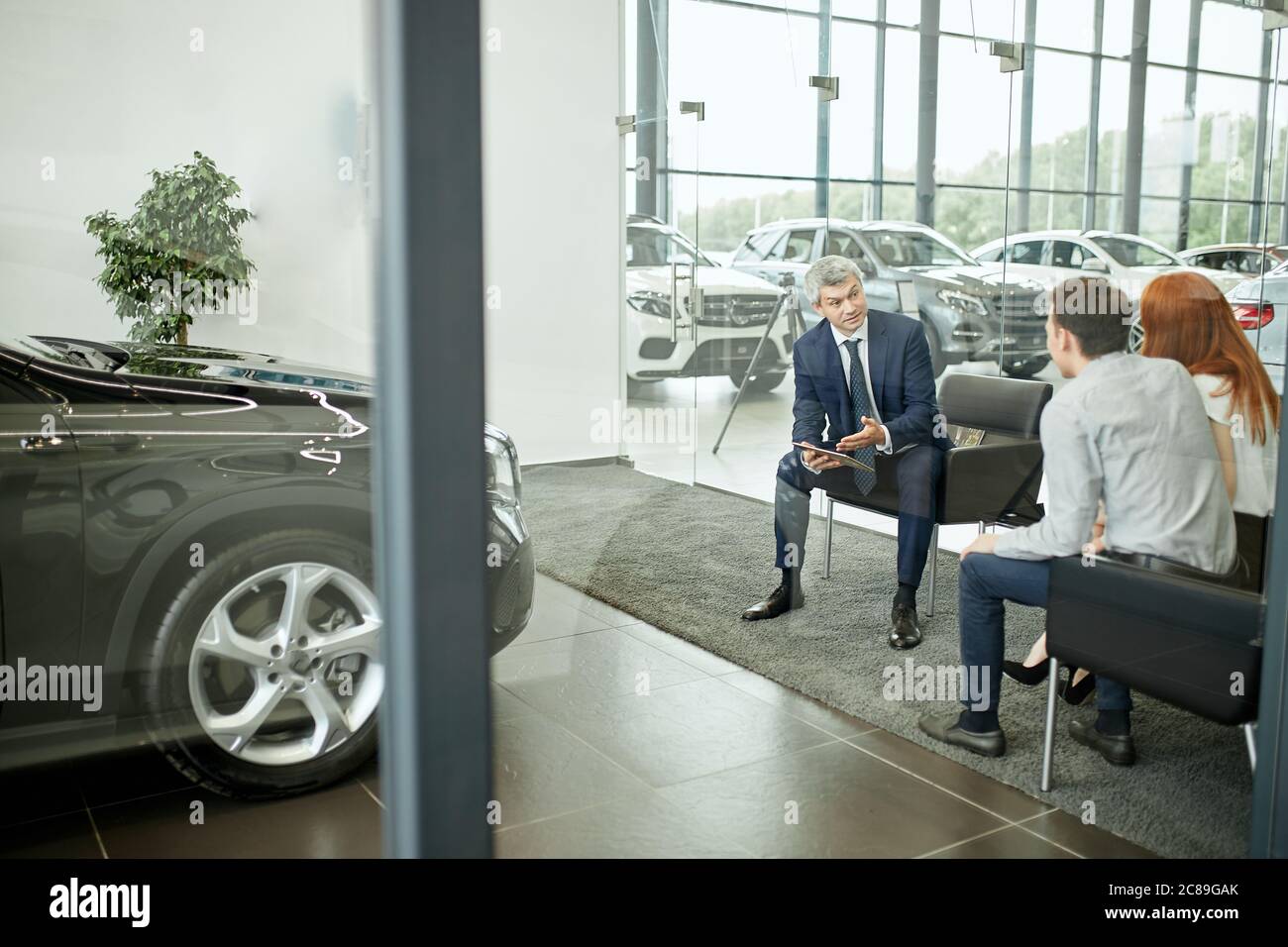 Sales agent at the table desk telling about car features to cheerful ...