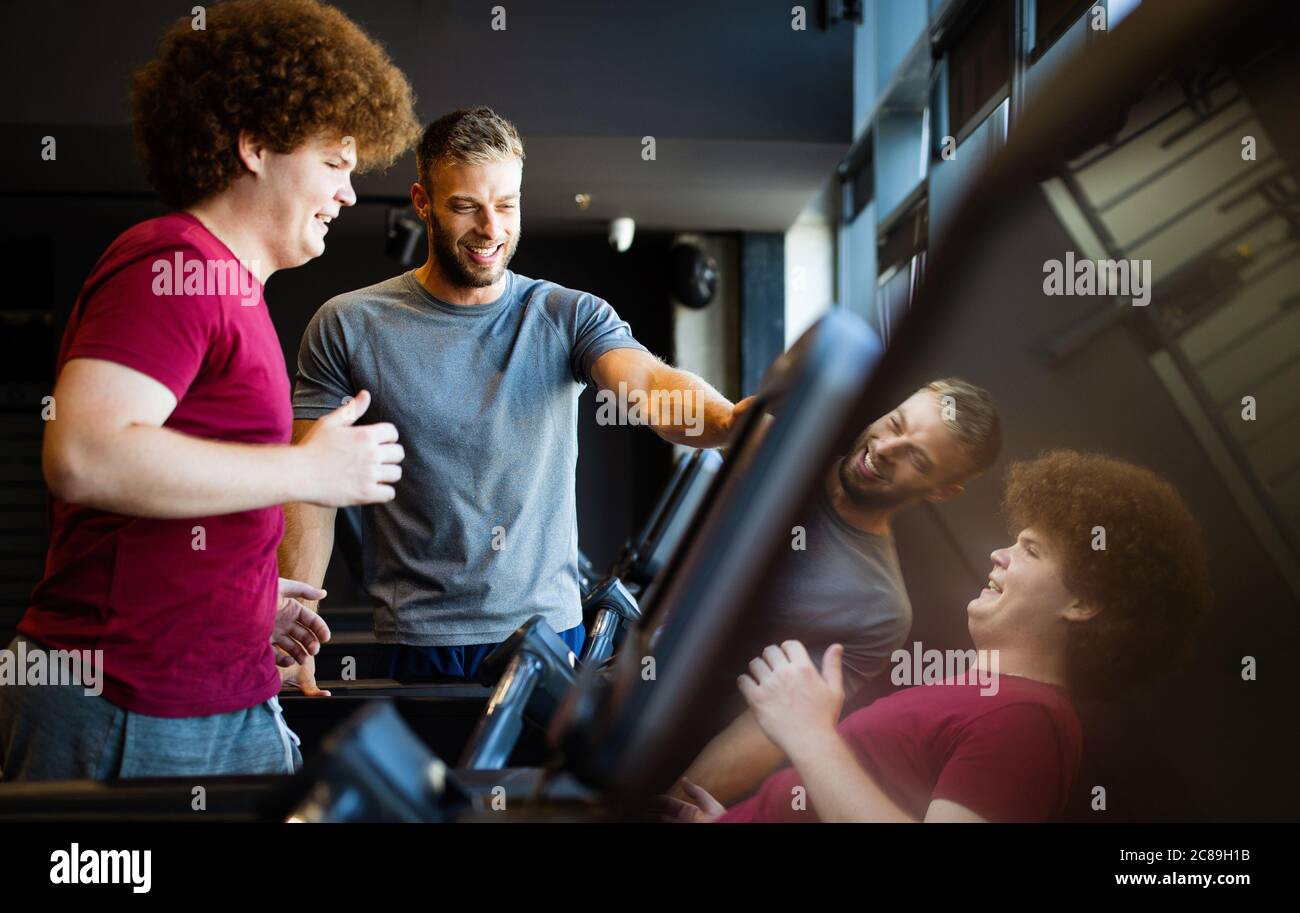 Fat young men with trainer exercising at fitness gym Stock Photo - Alamy