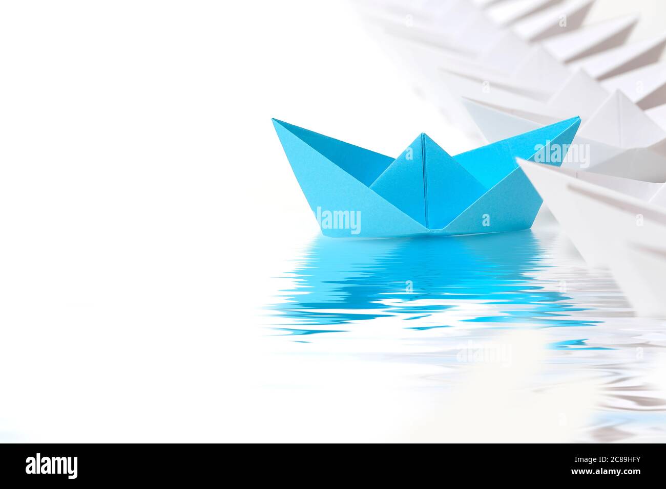 blue paper boat leading the race against white ones Stock Photo - Alamy