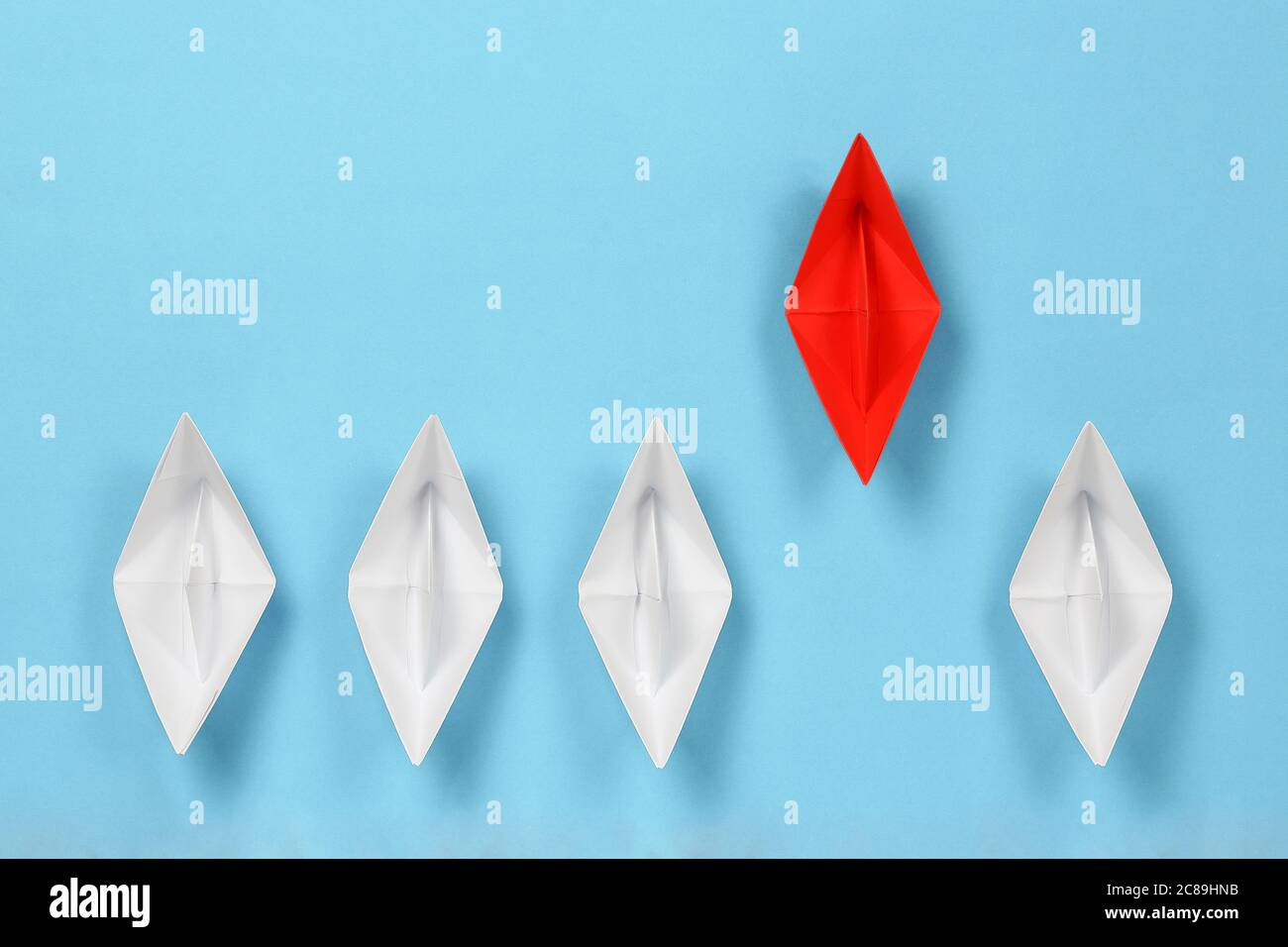 red paper boat leading the race against white paper boats, abstract ...