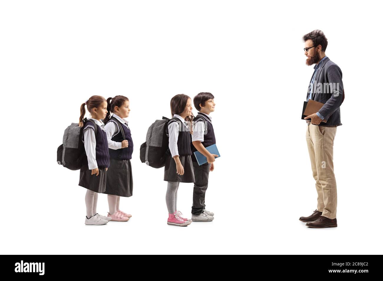Male teacher standing in front of a group of pupils in uniforms ...