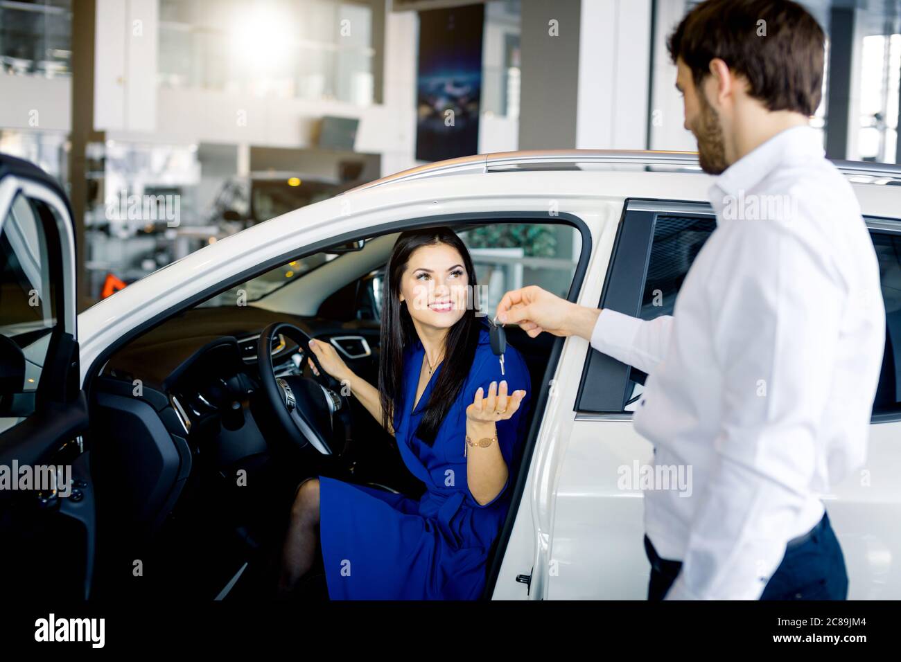 young smiling woman sitting in car taking key handover rent purchase ...