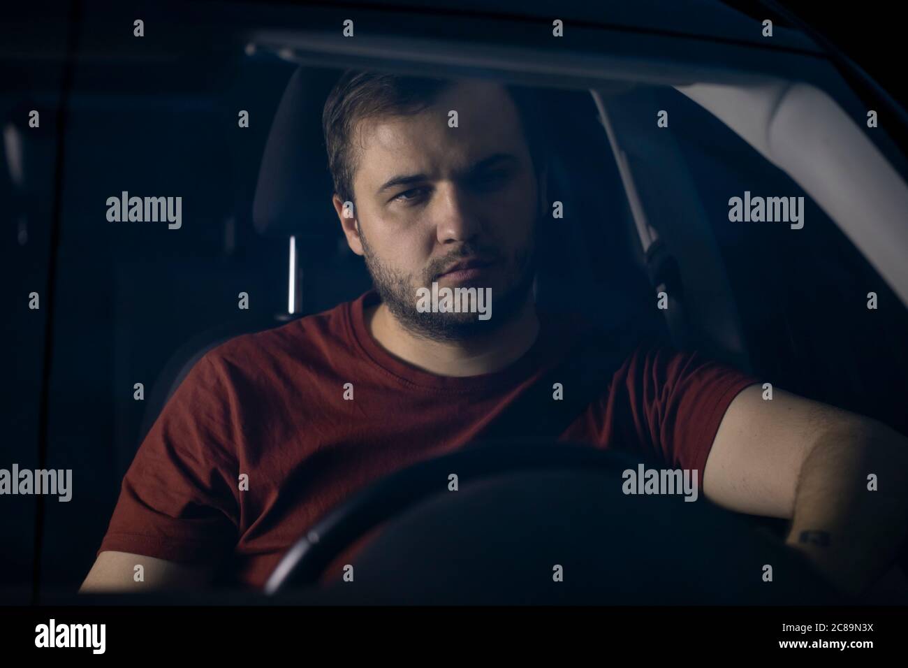 Caucasian Young man driving a car rides at night Stock Photo - Alamy