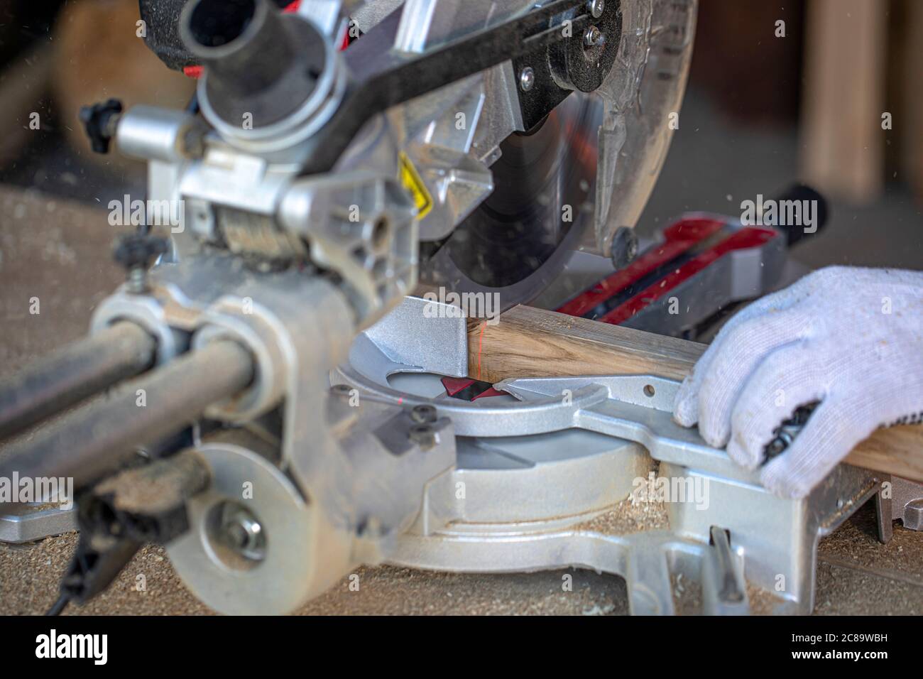 Carpenter cuts a timber beam with a circular saw. A closeup of hands in ...