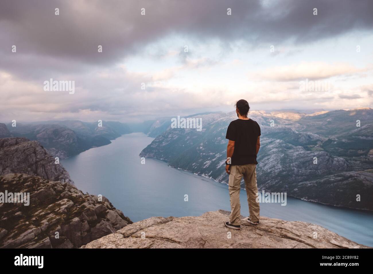 Man standing at edge of cliff at Preikestolen, Norway Stock Photo - Alamy