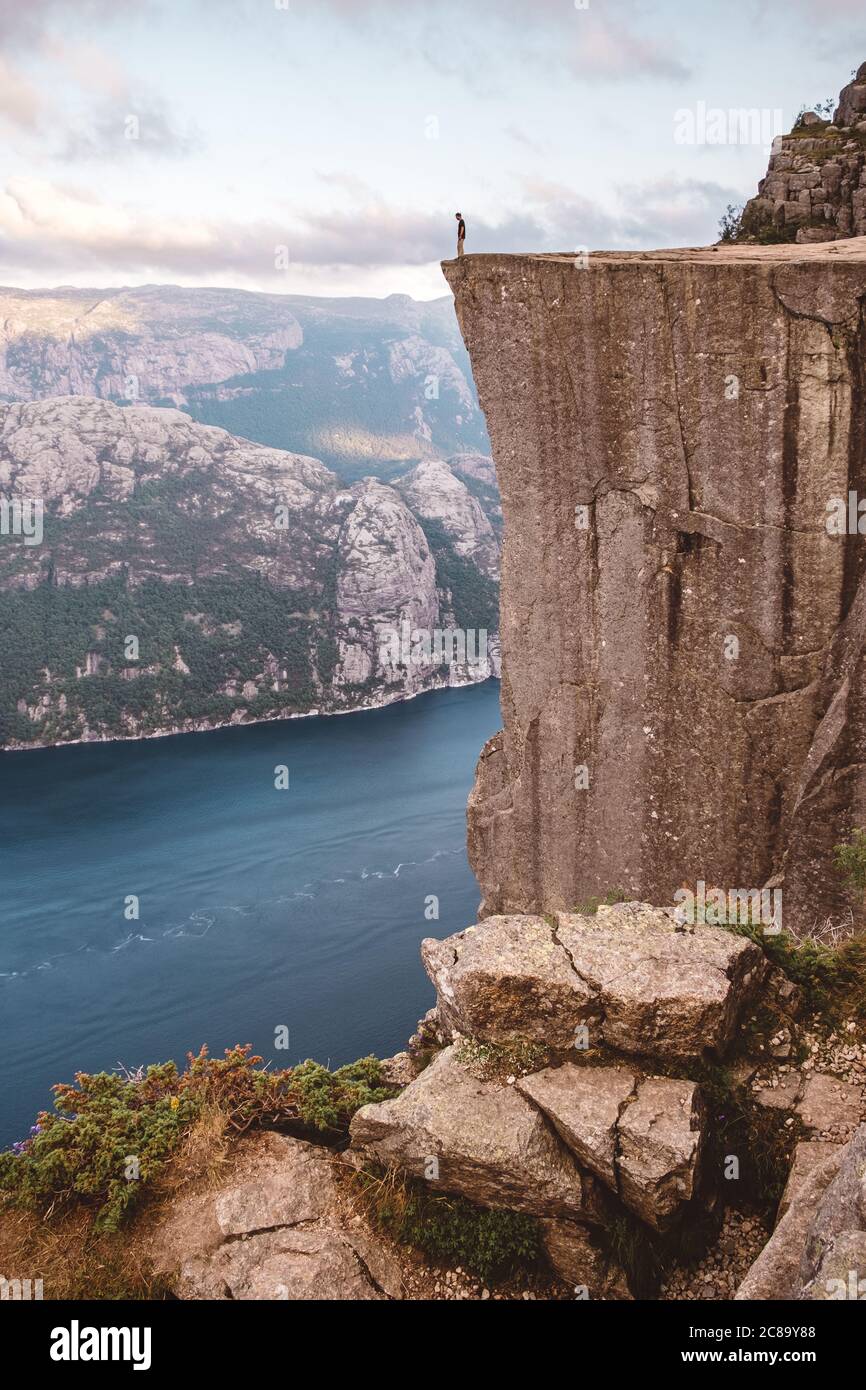 Man standing looking down at edge of cliff at Preikestolen, Norway ...