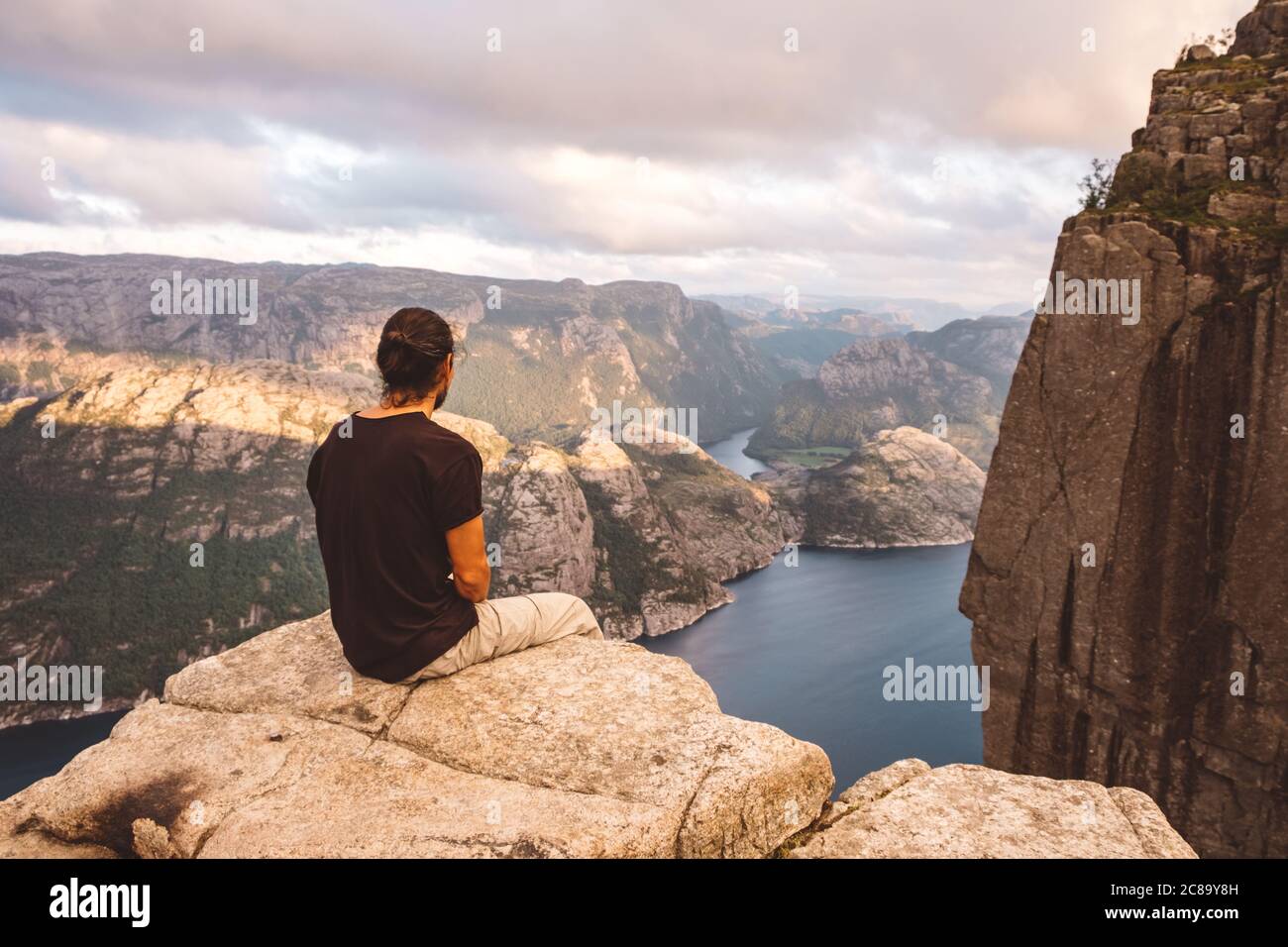 Man sitting in rock at edge of cliff at Preikestolen, Norway Stock ...