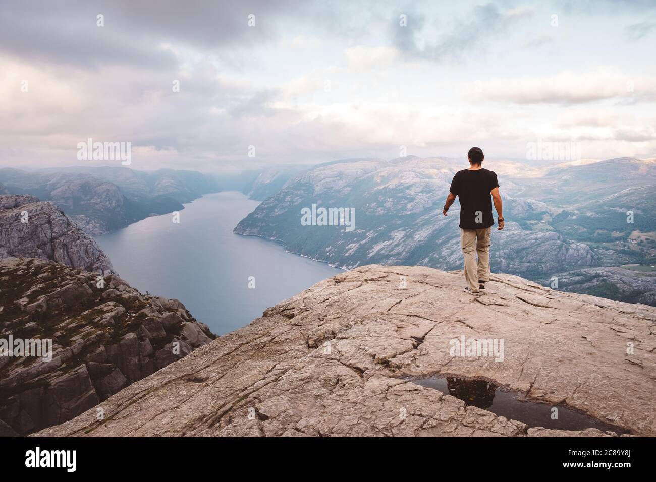Man walking at edge of cliff at Preikestolen, Norway Stock Photo - Alamy
