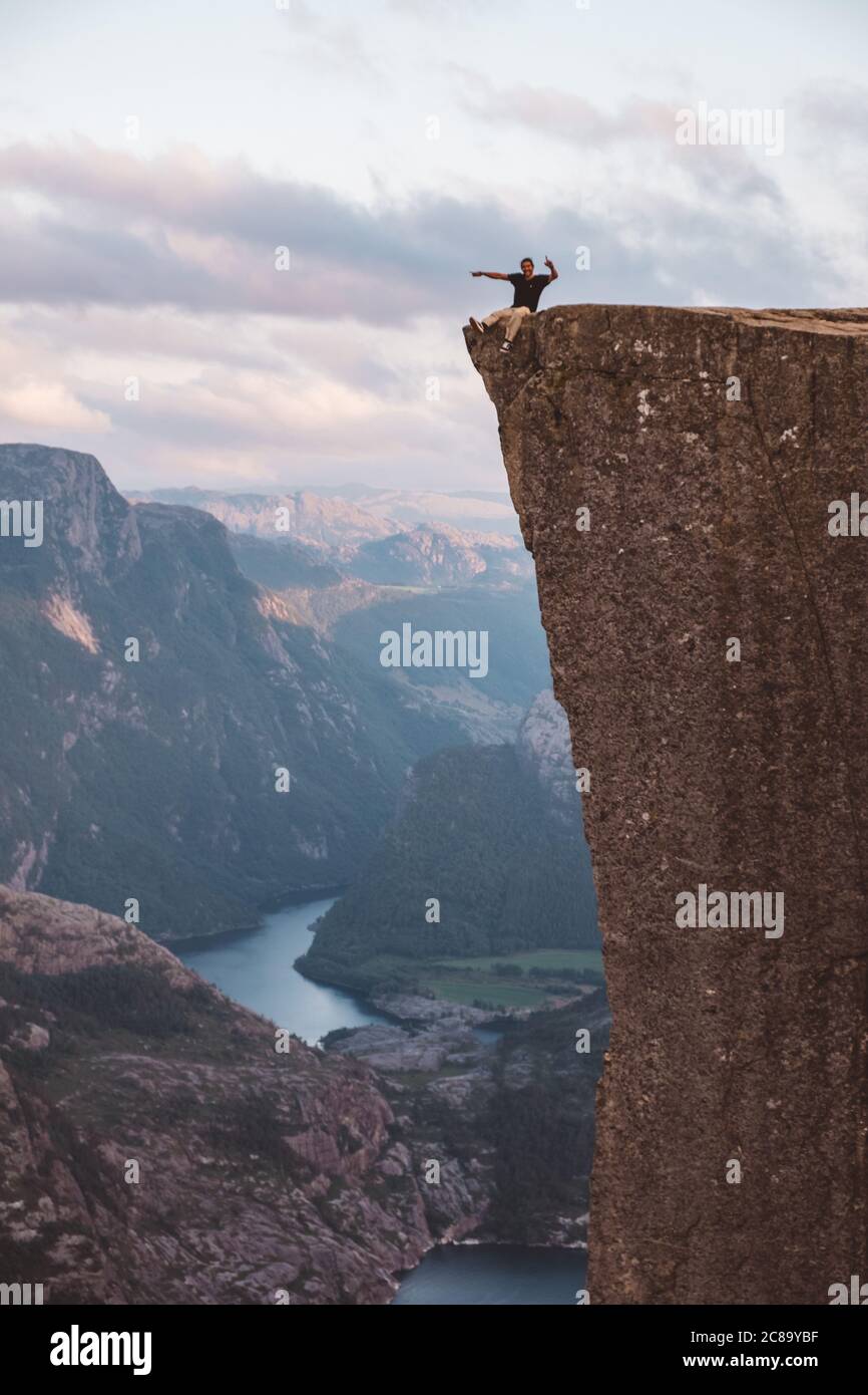Man sitting at edge of cliff at Preikestolen, Norway Stock Photo - Alamy