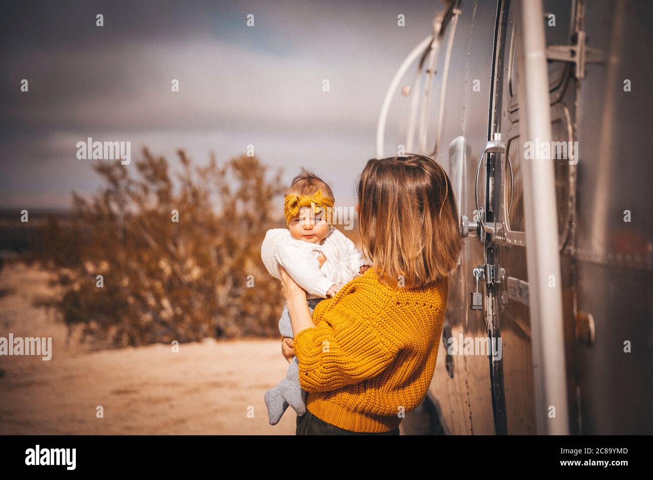 A woman with a baby is near an RV trailer, Joshua Tree, California ...