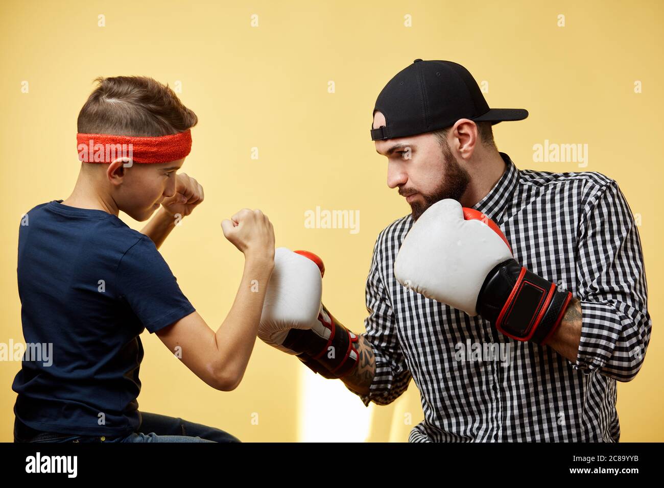 Father and son during boxing training, on yellow background Stock Photo ...