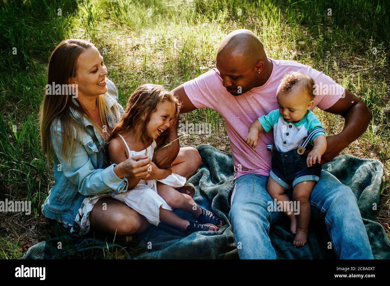 Happy young family laughing and smiling while sitting in grass Stock ...