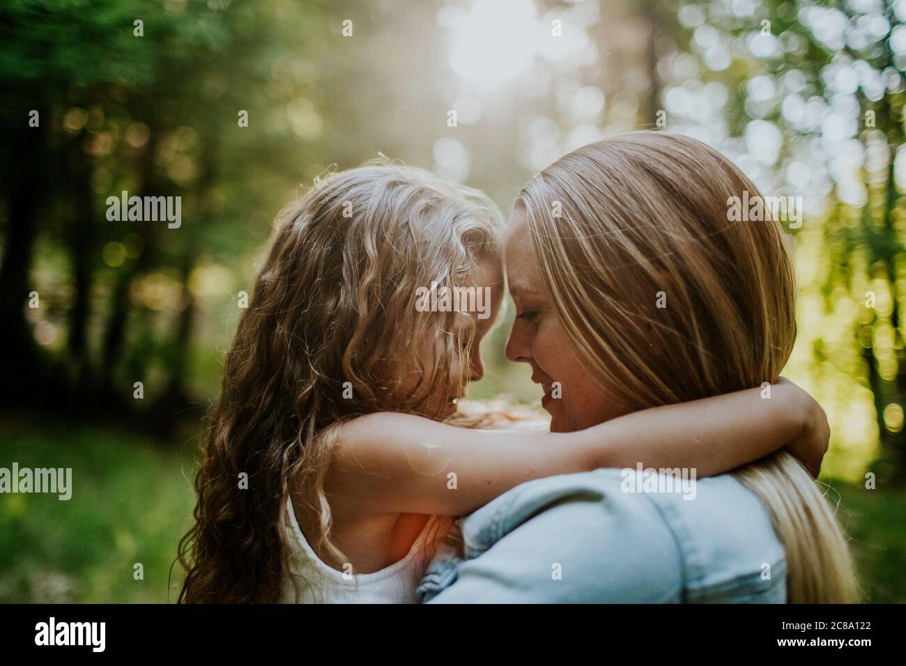 Mom and young daughter hugging smiling in afternoon sun Stock Photo - Alamy