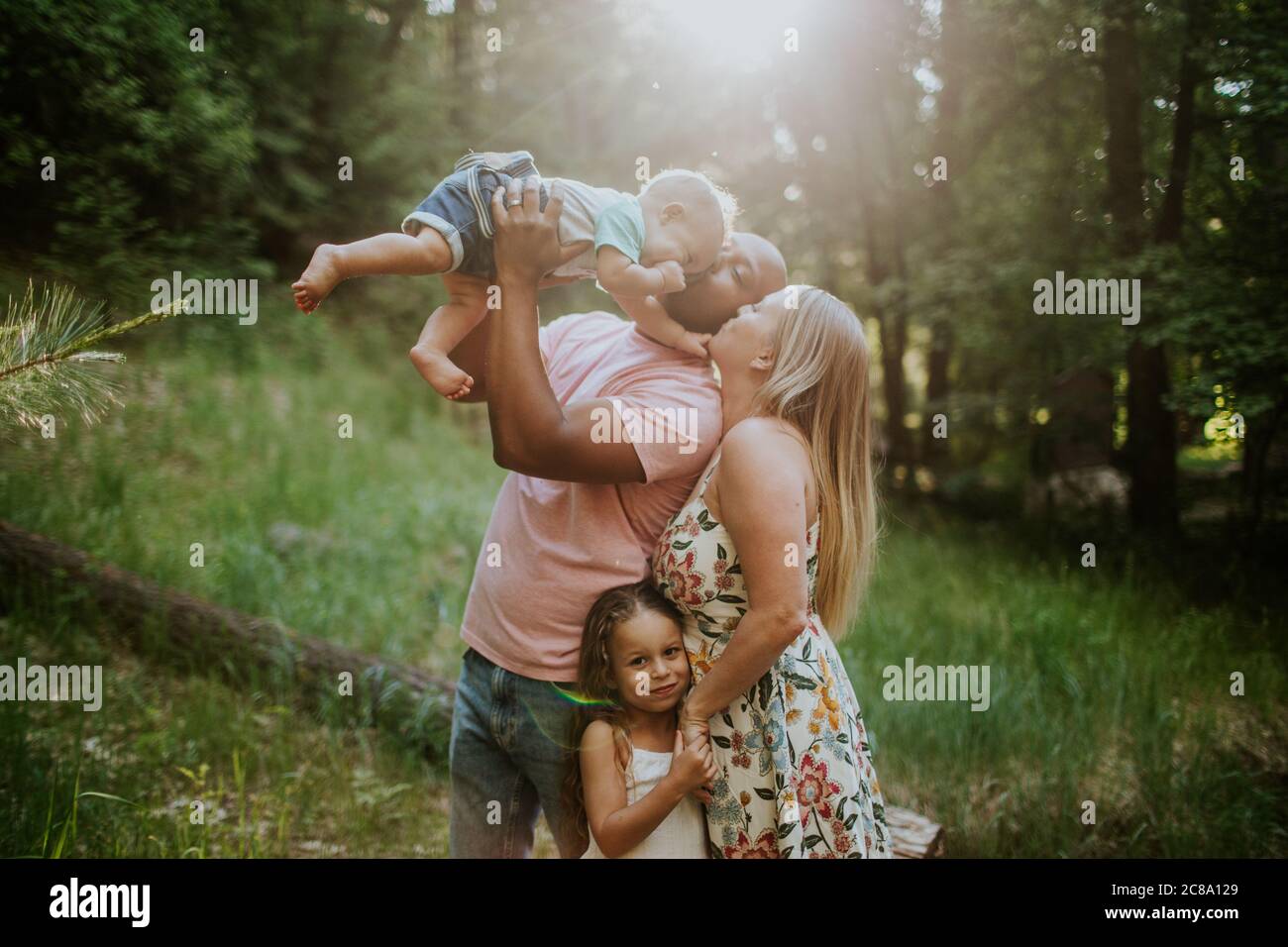Family of four snuggling and kissing in forest Stock Photo - Alamy