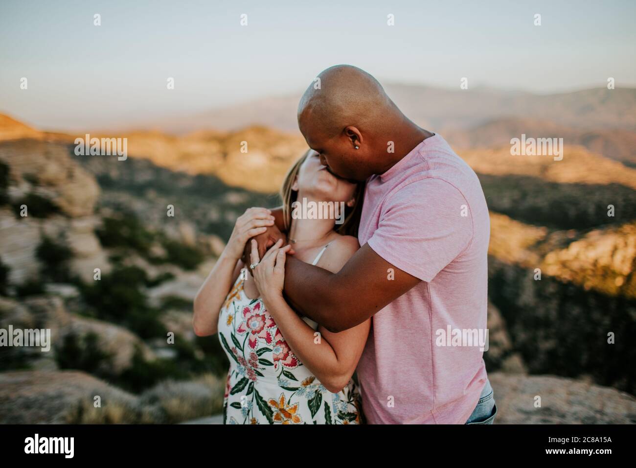 Multiracial couple kissing on top of mountain Stock Photo - Alamy