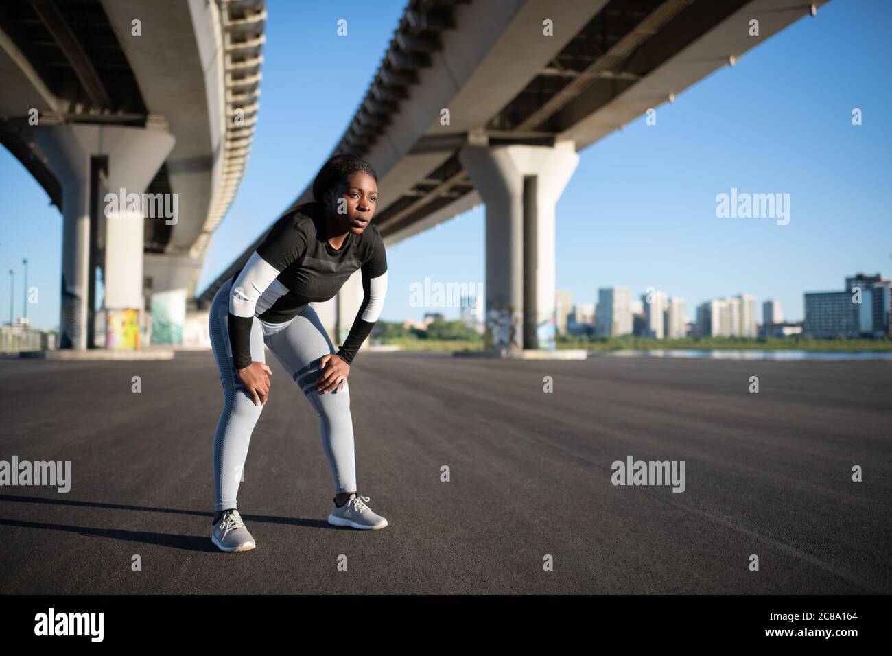 Tired black runner leaning forward and breathing during break in ...