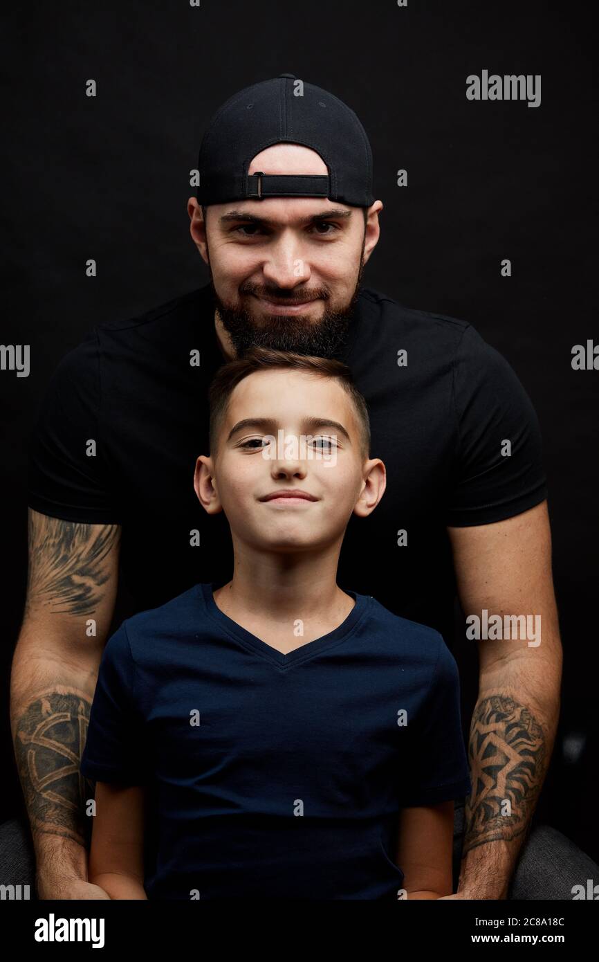 Portrait bearded father and little son smile for camera on black ...