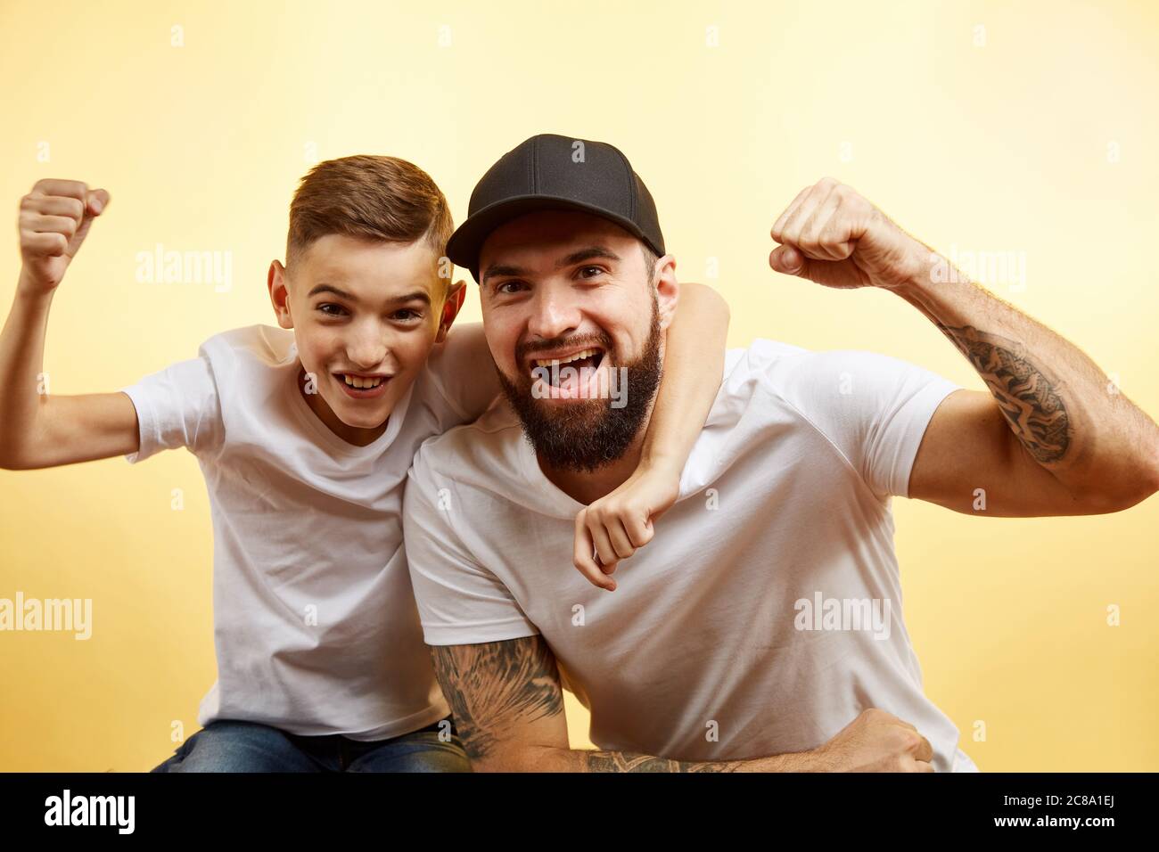 Father and son celebrating their success. raised up arms on yellow ...