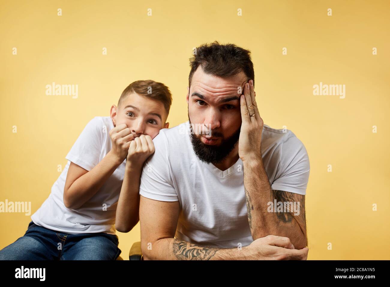 boy and father bite nails and look camera on yellow background Stock ...