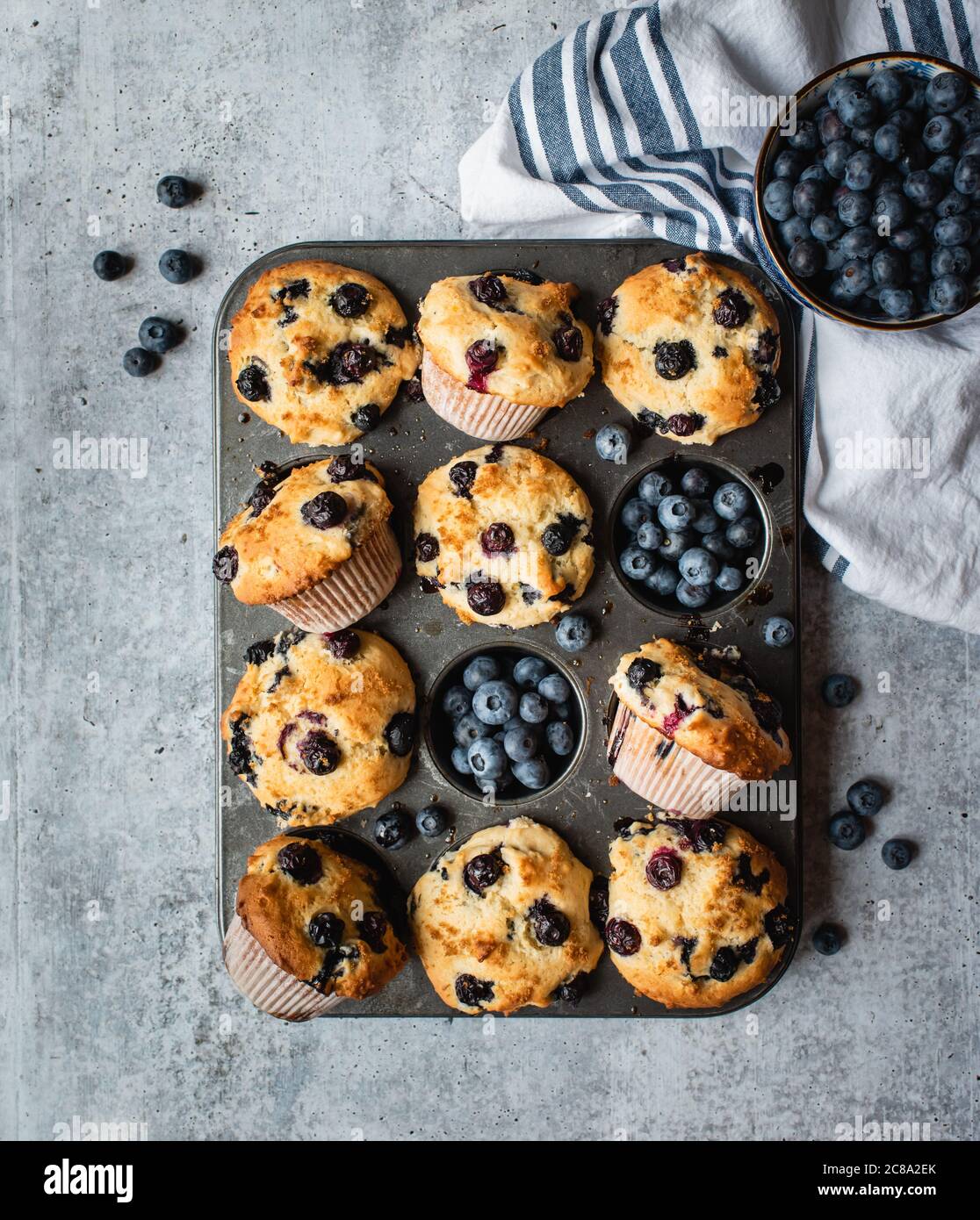 Overhead view of blueberry muffins in baking tin on concrete counter ...