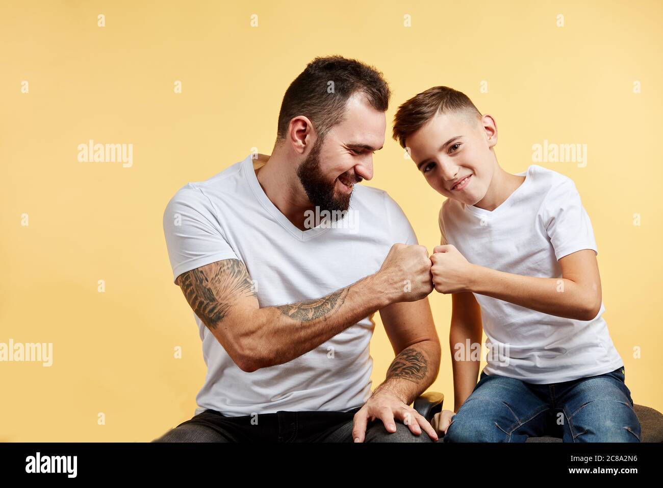 smiling father and son with pleasant smile give fist bump to each other ...