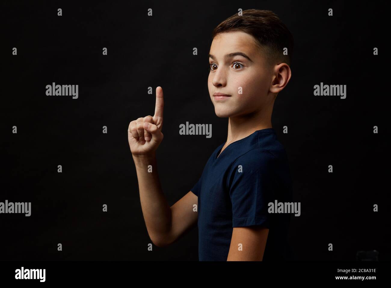 Cheerful teen boy pointing up over black background Stock Photo - Alamy
