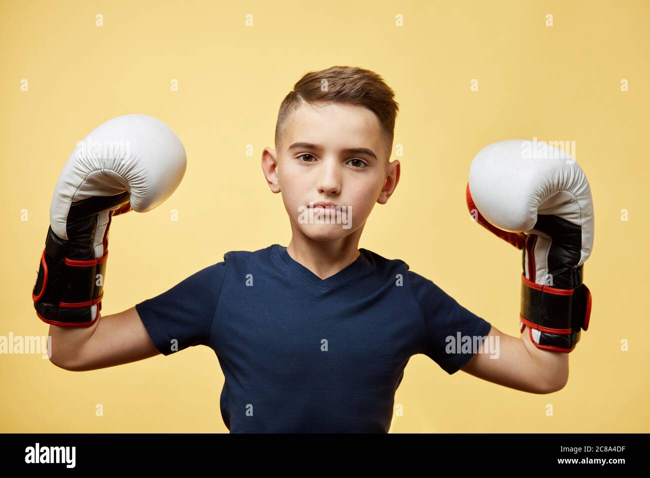 smiling young child with big boxing gloves winning competition, yellow ...