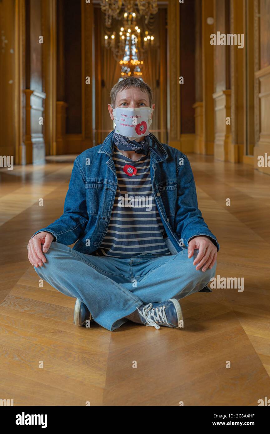 Paris, France - 06 19 2020: A masked woman sitting on the wooden floor ...