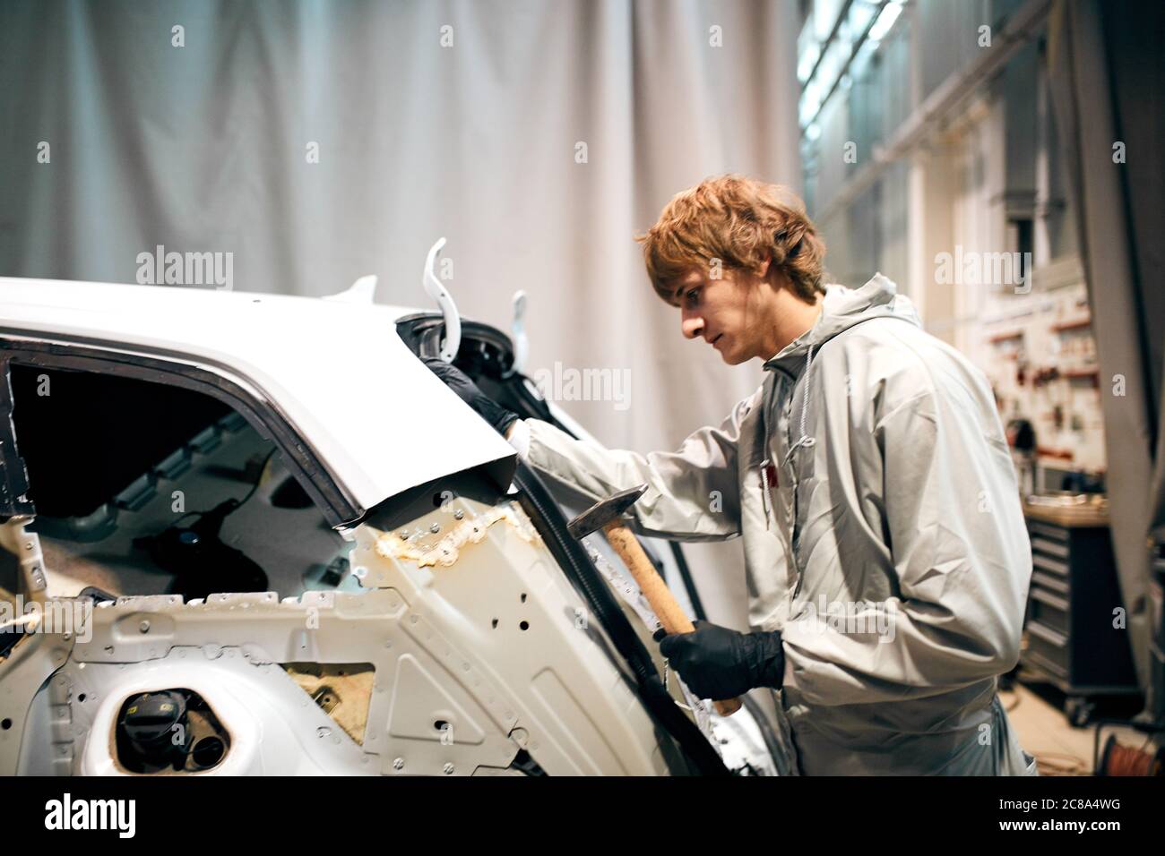 auto repair worker flatten and align metal body car with hammer in ...