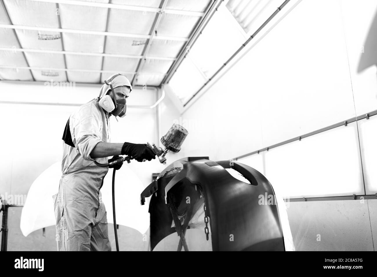 auto mechanic worker painting car bumper in paint chamber during repair ...