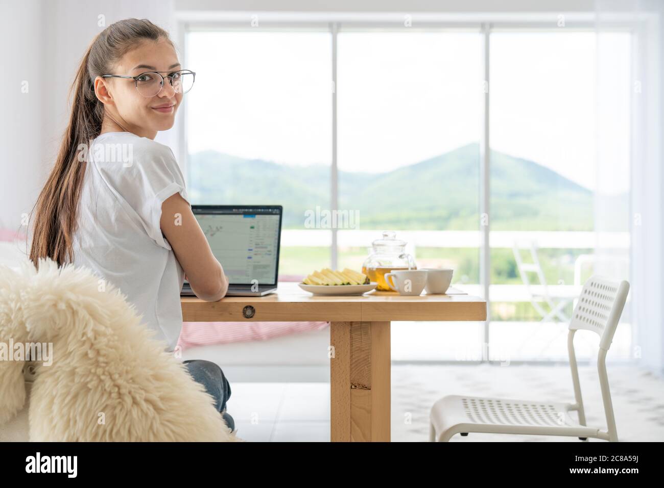 Cheerful woman using laptop at home. Young girl working on computer ...