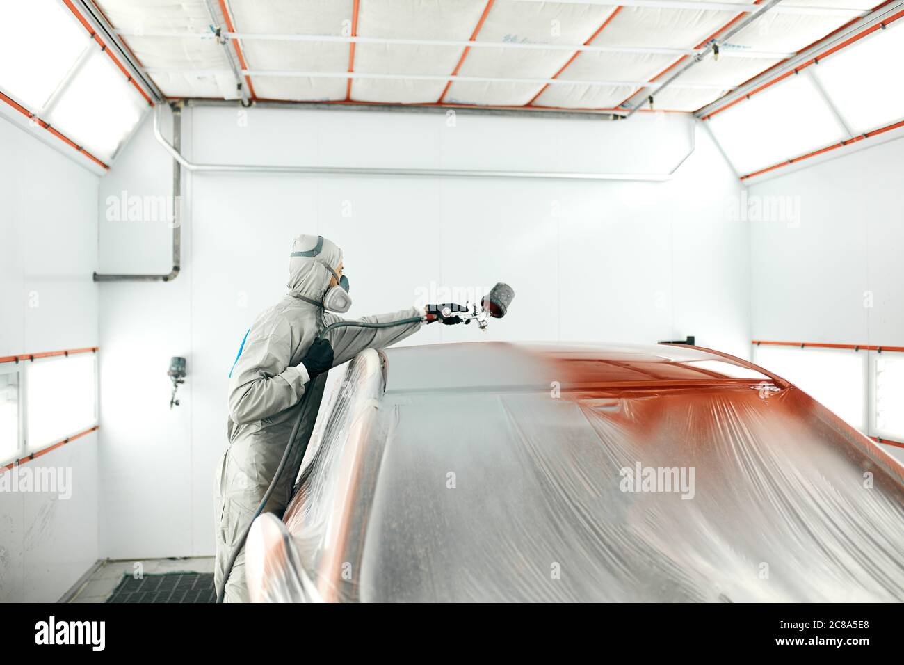 Car body painter spraying paint in garage or workshop with airbrush ...