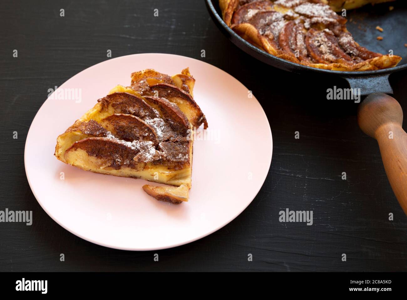 Homemade Apple Dutch Pannekoek Pancake on a pink plate on a black ...