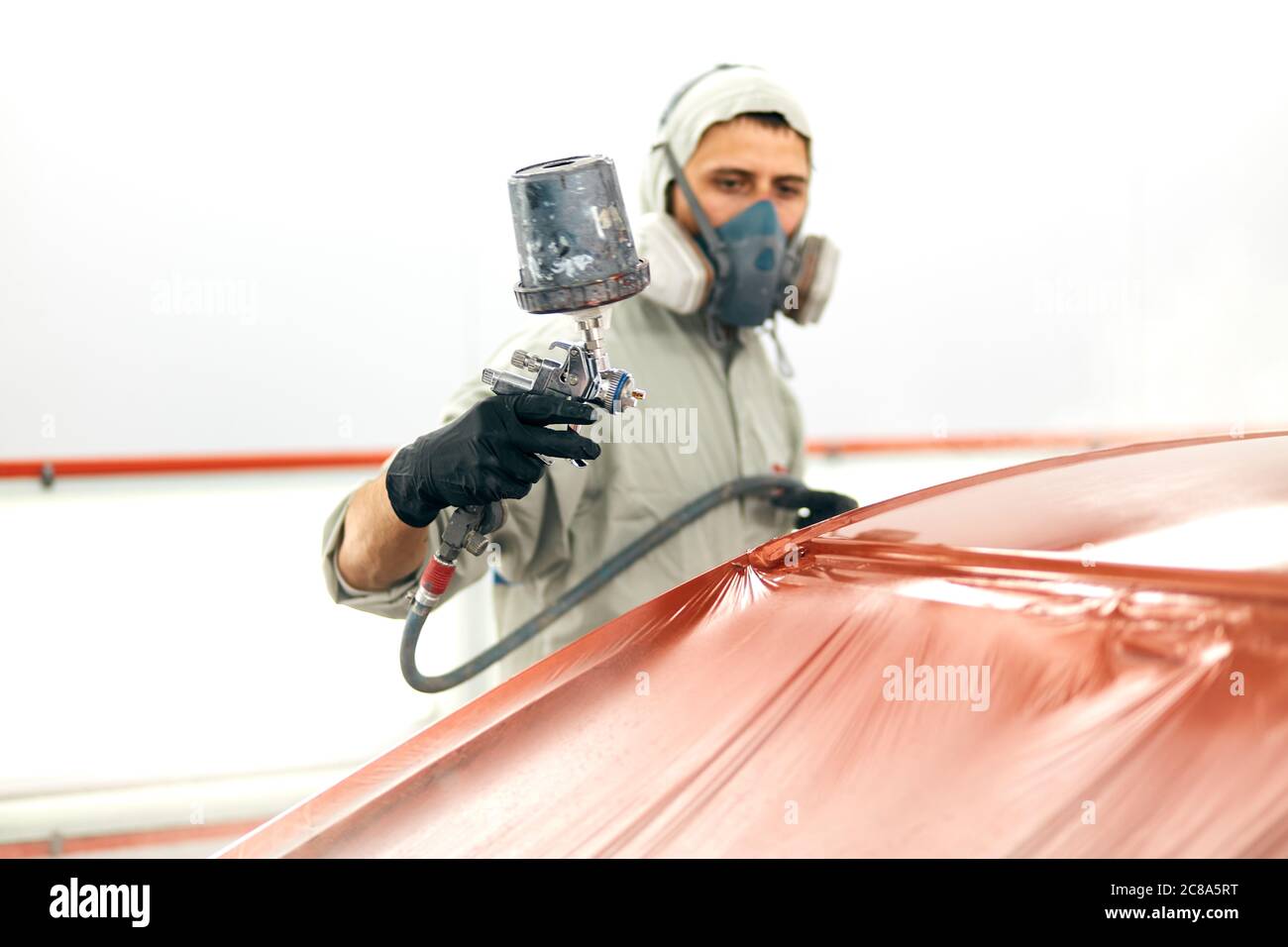 Car body painter spraying paint in garage or workshop with airbrush ...
