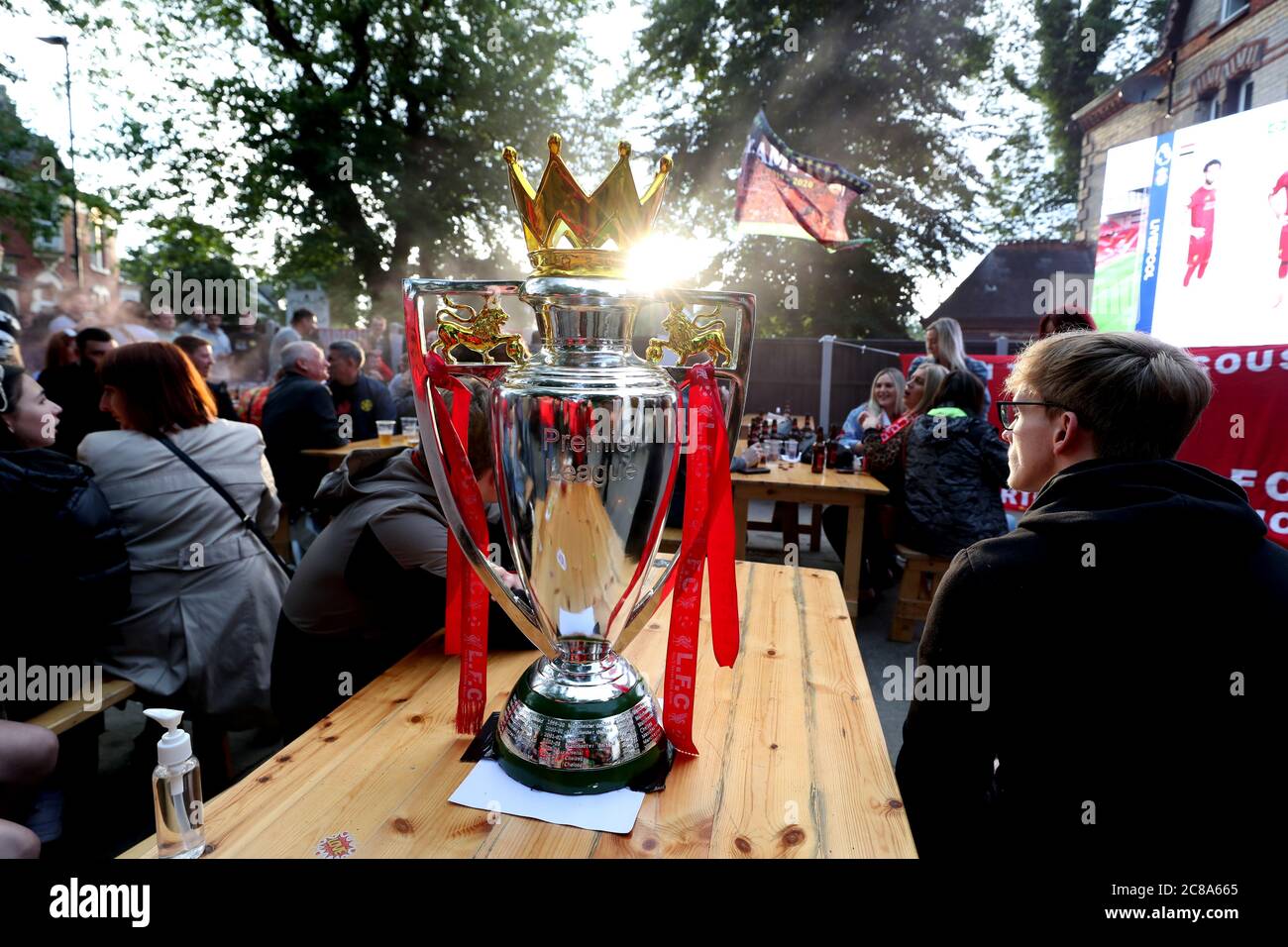 A replica Premier League trophy rests on a pub table as fans watch ...