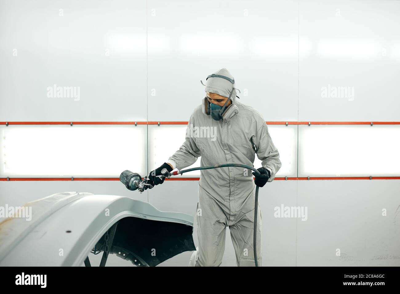 auto mechanic worker painting car bumper in paint chamber during repair ...
